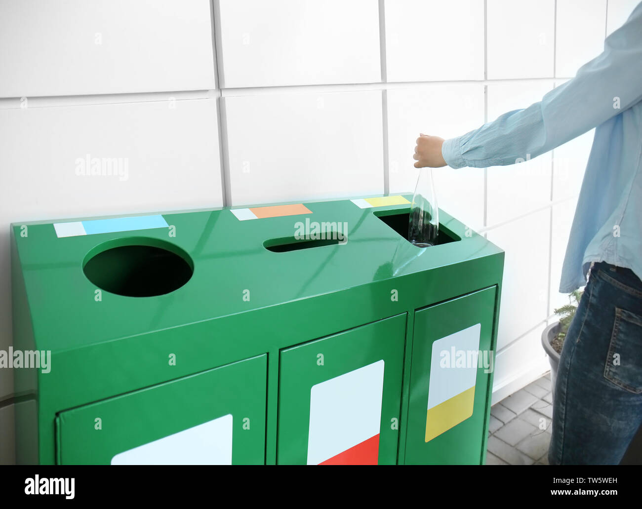 Woman throwing glass bottle into litter bin outdoors Stock Photo - Alamy