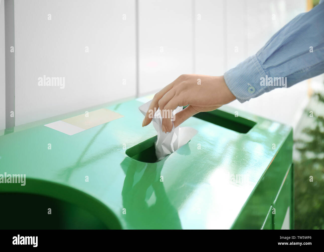Woman throwing paper into litter bin outdoors Stock Photo - Alamy