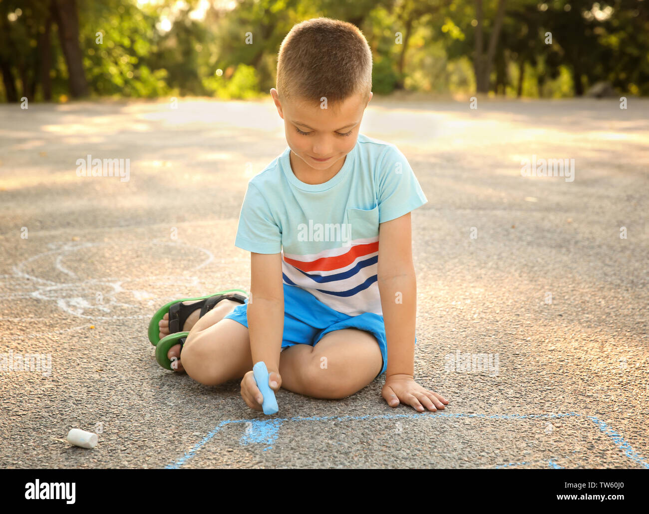 Cute little boy drawing with chalk, outdoors Stock Photo - Alamy