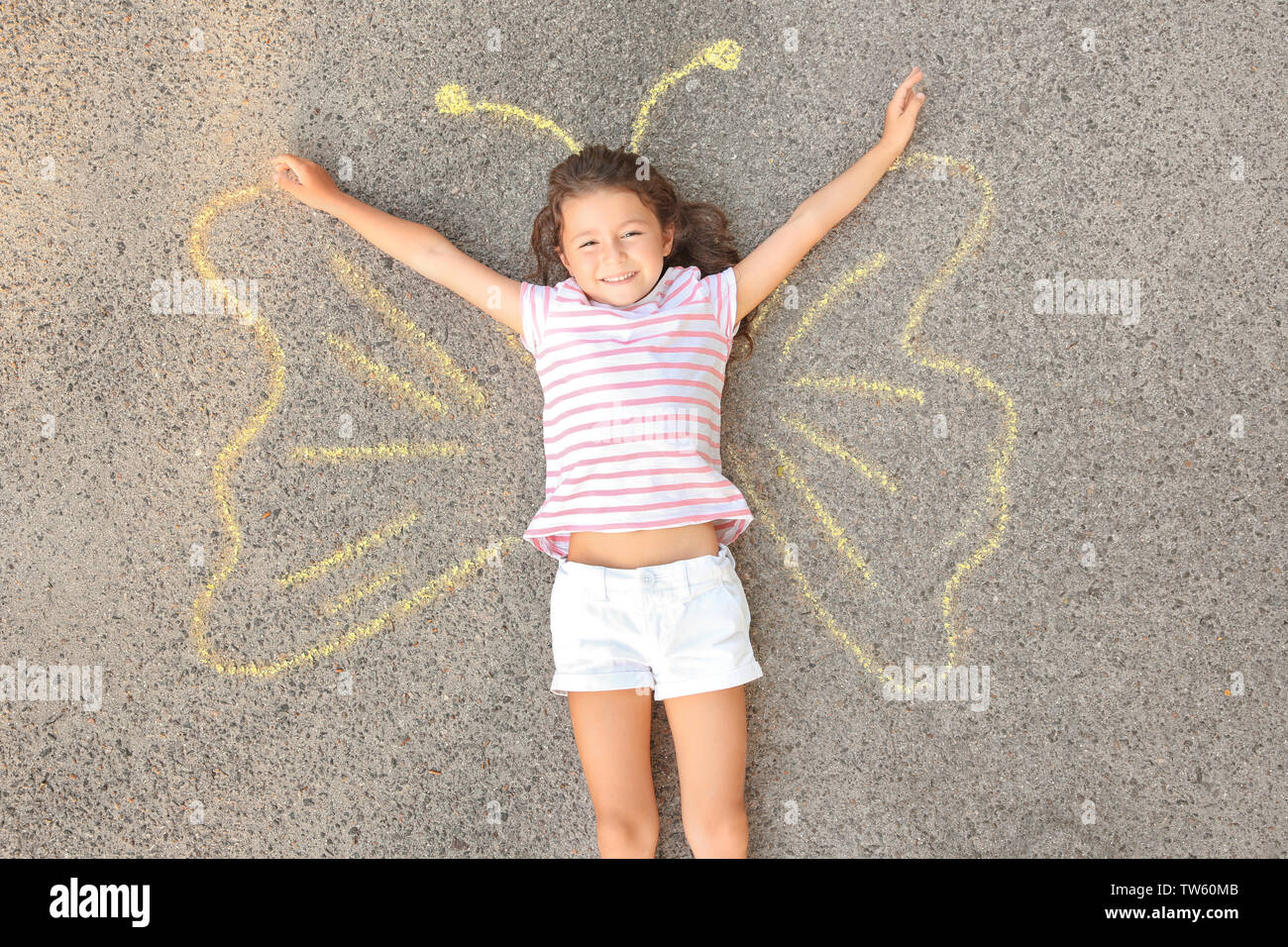 Cute little girl lying on asphalt, outdoors Stock Photo - Alamy