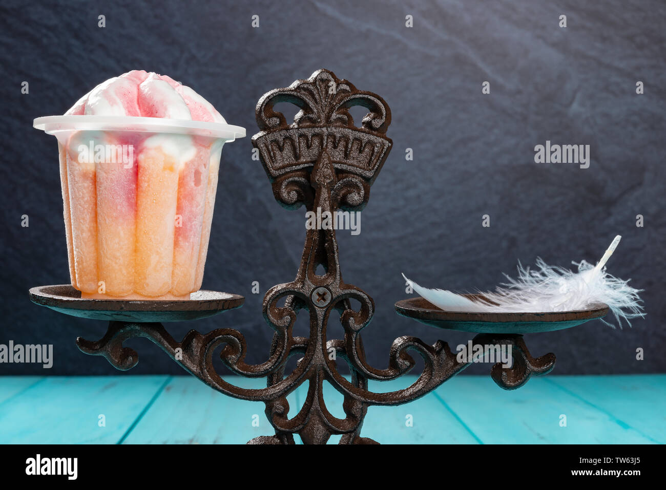 cup of ice cream close up and feather on a balanced scale concept of ...