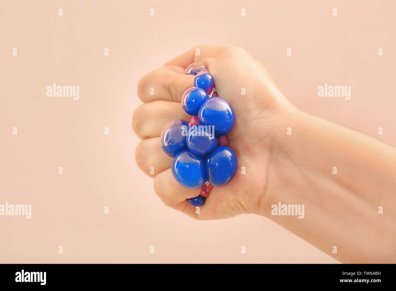 Woman's hand squeezing trendy stress ball on apricot background Stock ...