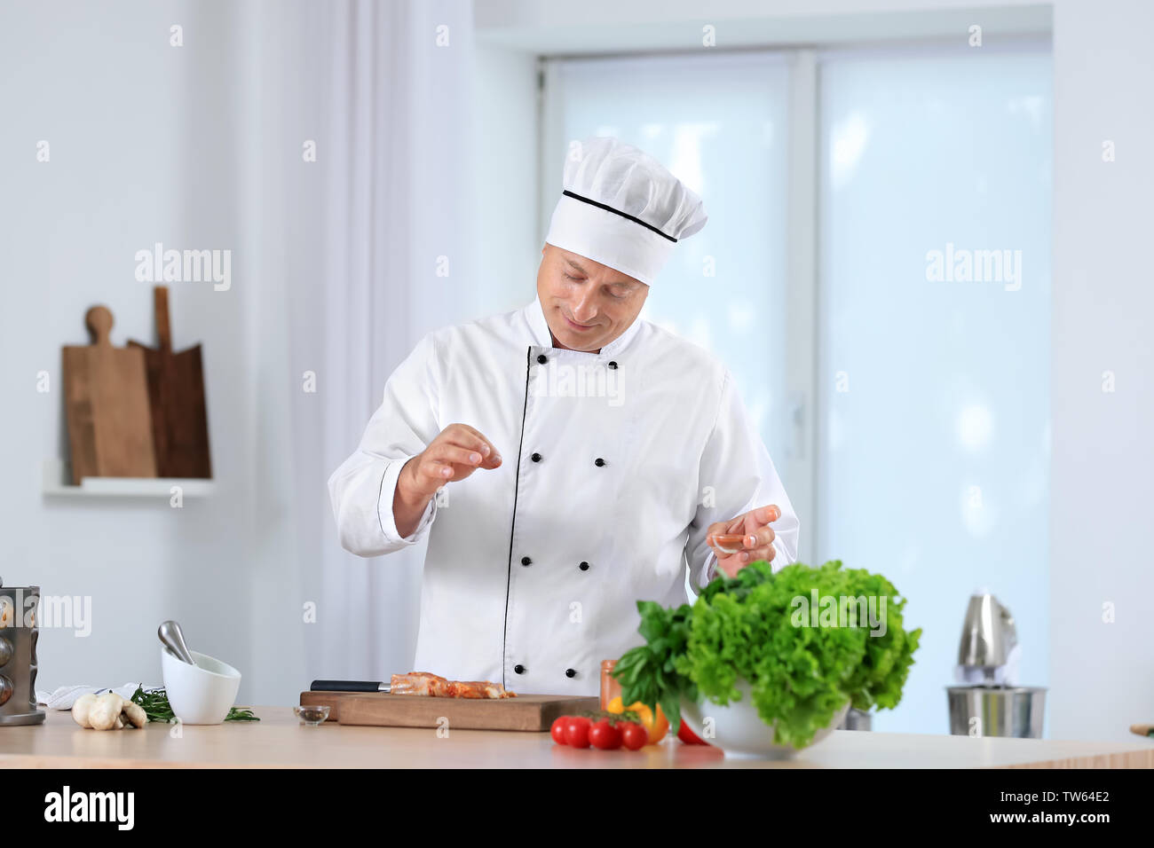 Male chef adding seasoning to meat in kitchen Stock Photo - Alamy