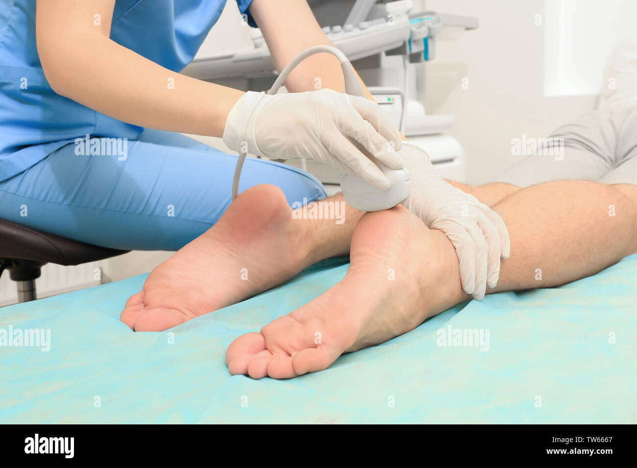 Doctor conducting ultrasound examination of patient's foot in clinic ...