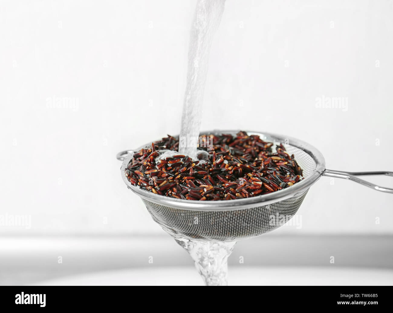 Washing raw rice with water in kitchen Stock Photo - Alamy