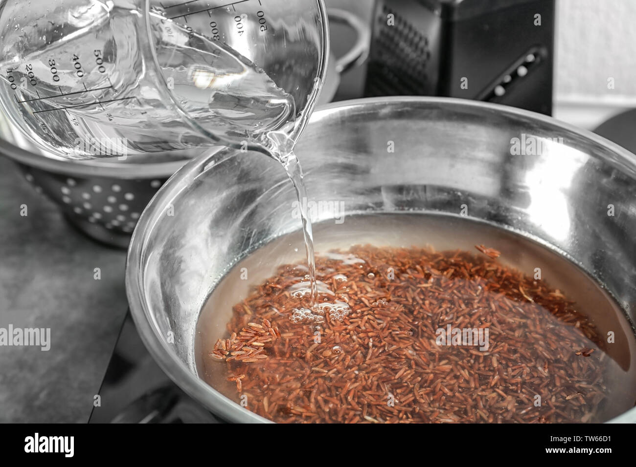 Pouring water into bowl with boiling rice Stock Photo - Alamy