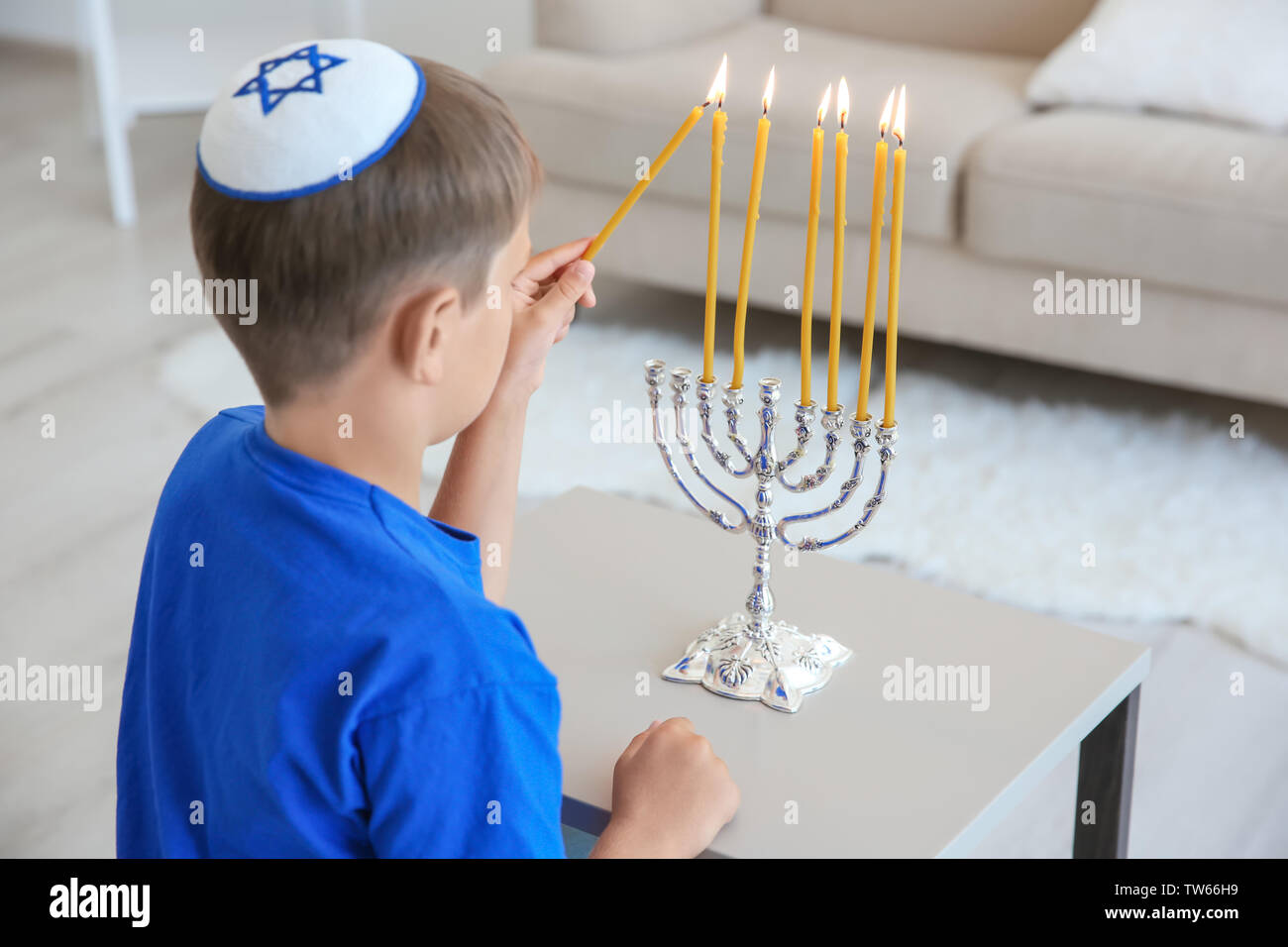 Jewish boy lightning menorah at home Stock Photo - Alamy