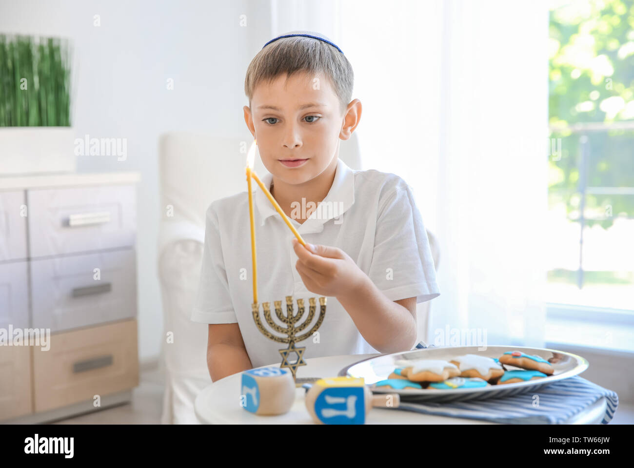 Jewish boy lightning menorah at home Stock Photo - Alamy