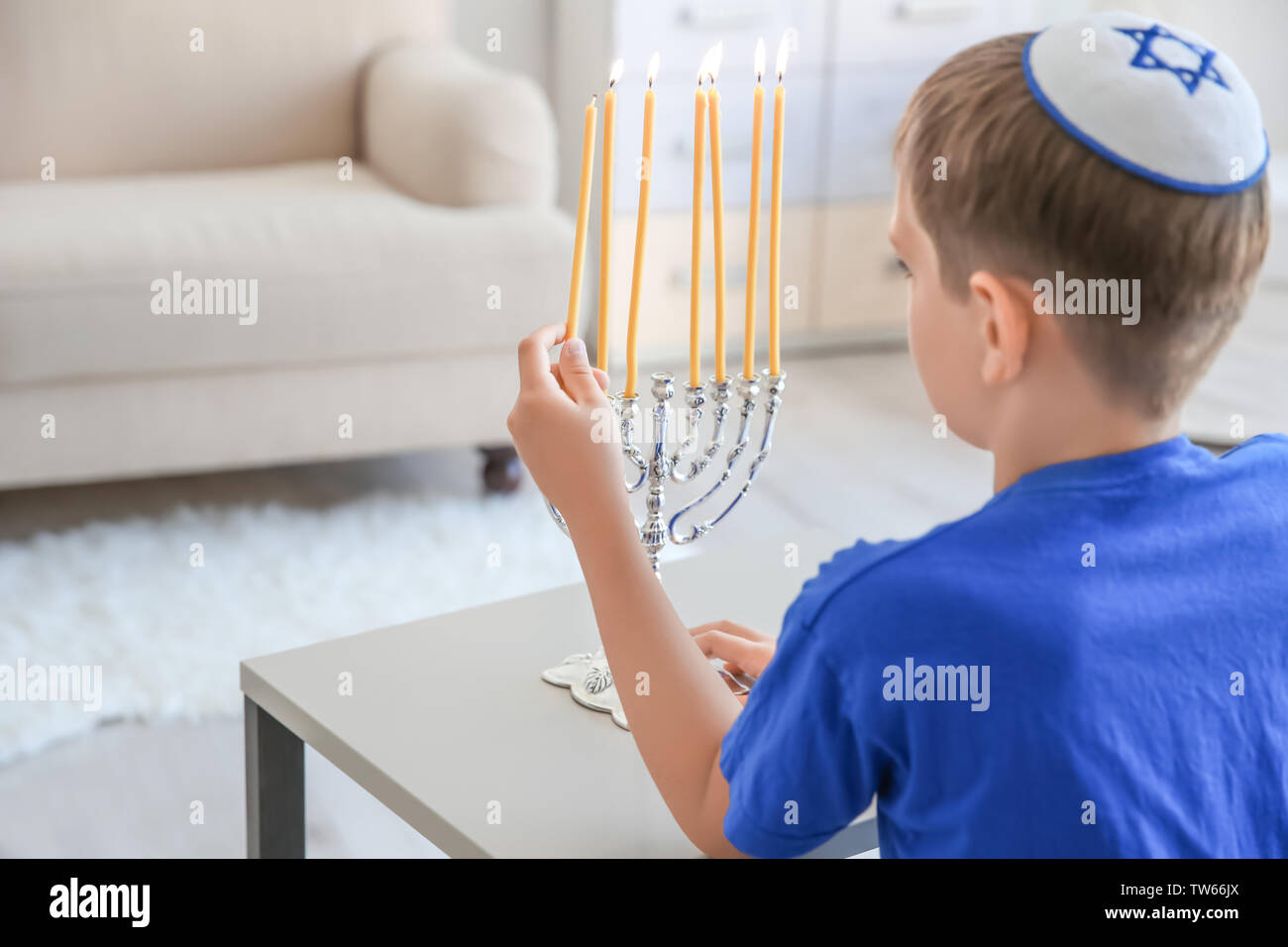 Jewish boy lightning menorah at home Stock Photo - Alamy