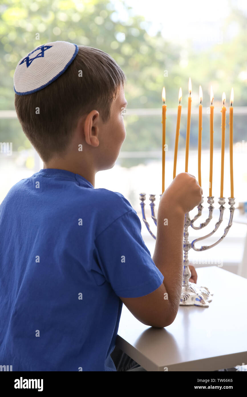 Jewish boy lightning menorah at home Stock Photo - Alamy