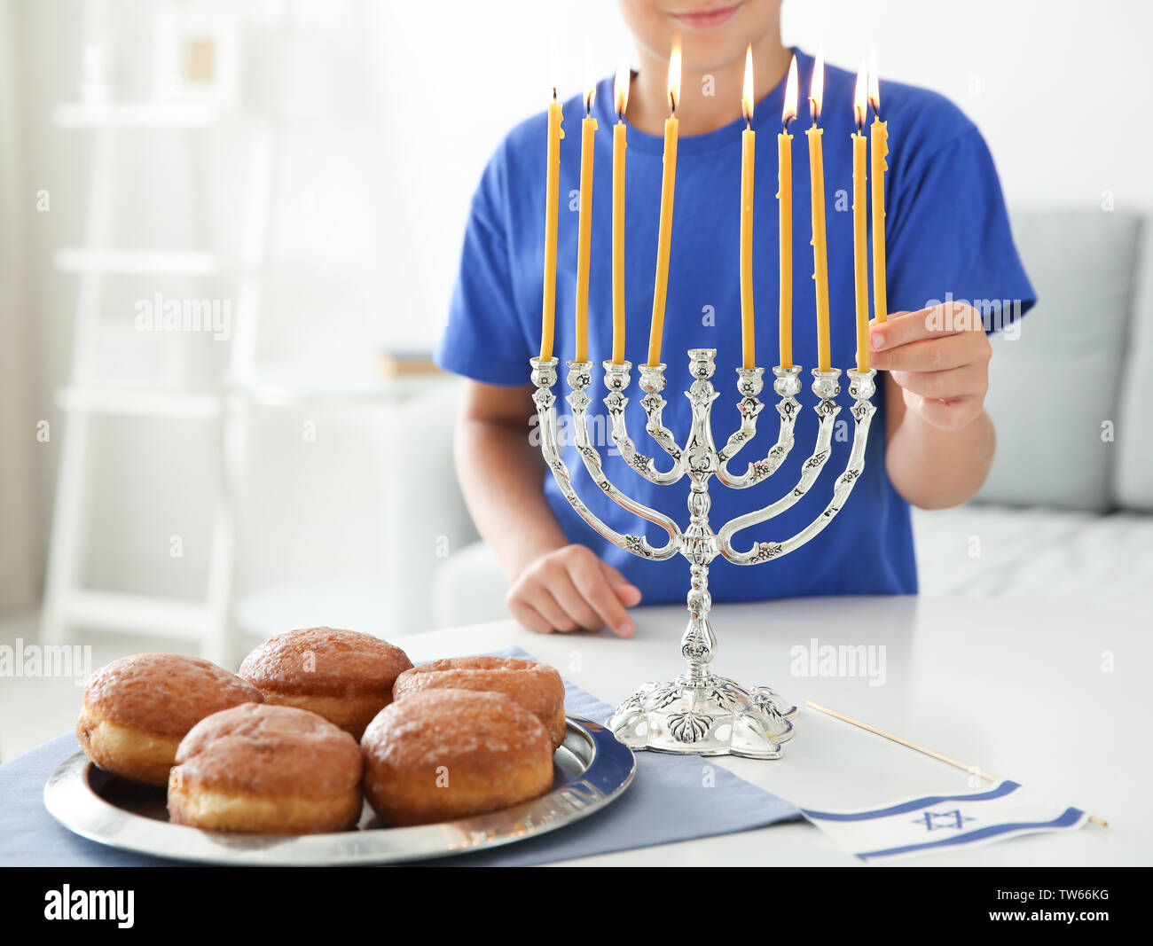 Jewish boy lightning menorah at home Stock Photo - Alamy