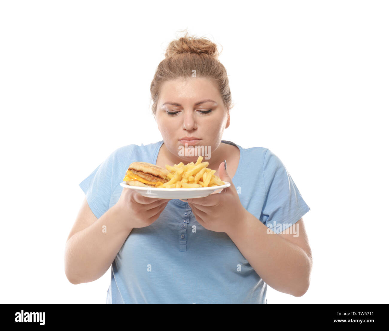 Overweight young woman with plate of fast food on white background ...