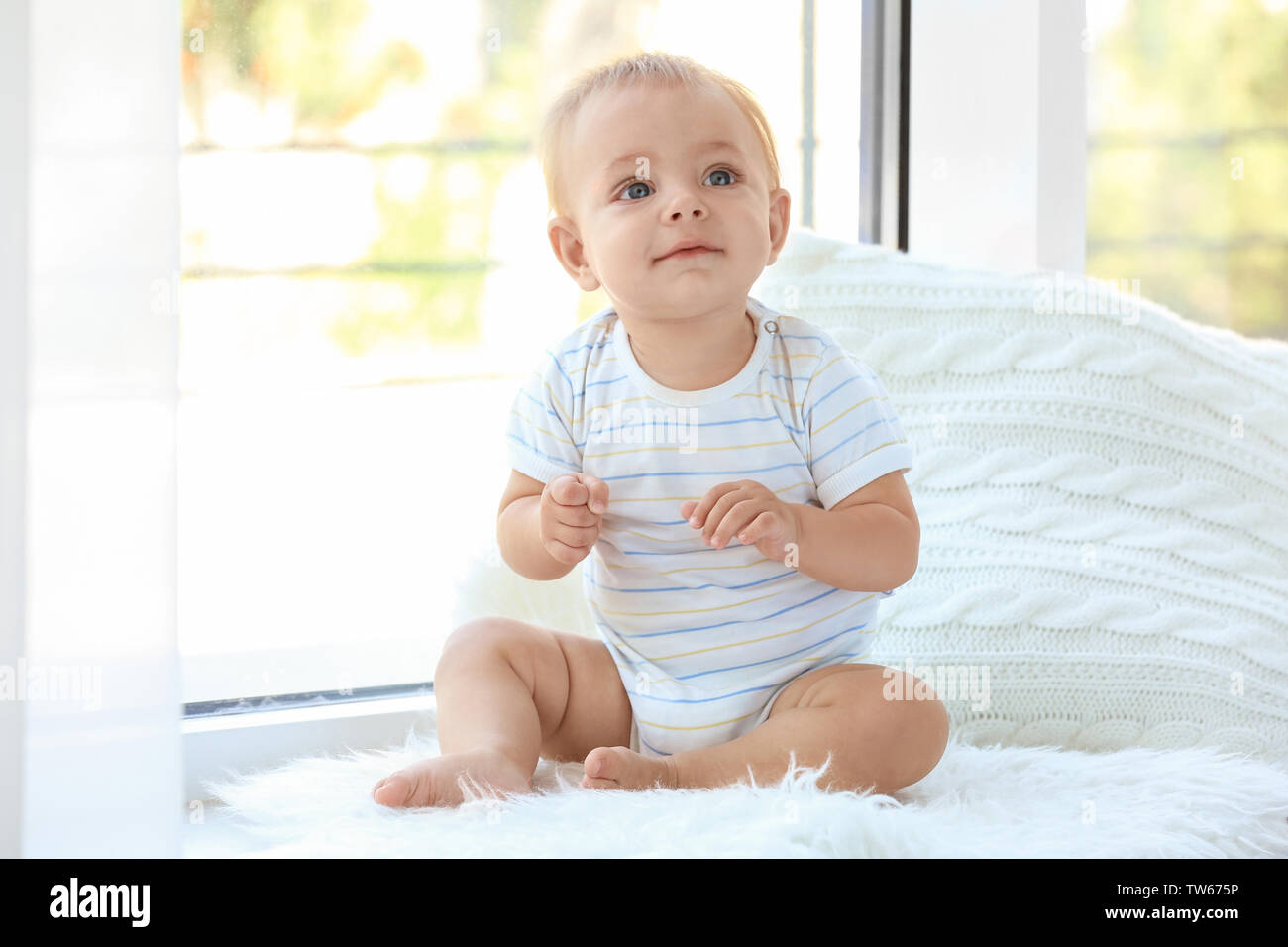Cute little baby sitting on window sill at home Stock Photo - Alamy