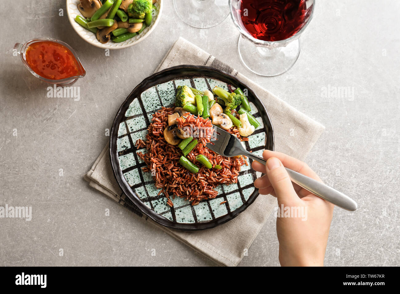 Woman eating delicious brown rice with vegetables Stock Photo - Alamy