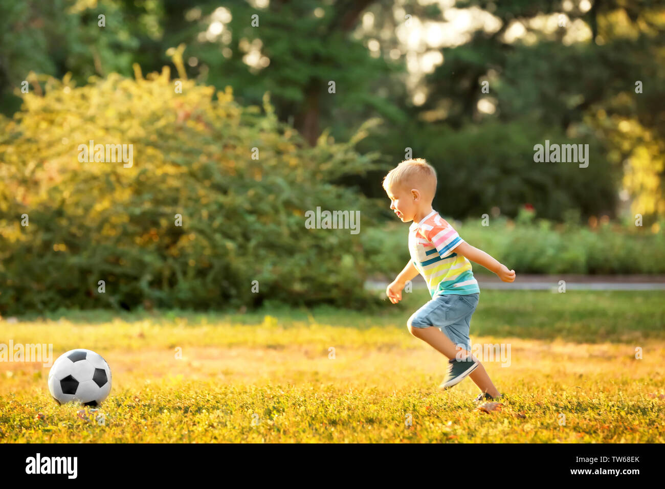 Cute boy playing football in park on sunny day Stock Photo - Alamy