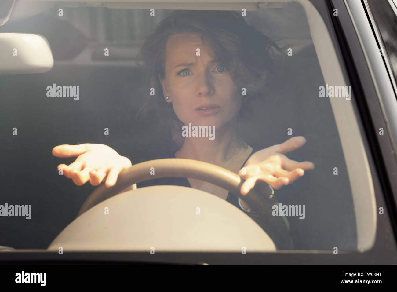 Emotional young woman driving a car, view from outside through ...