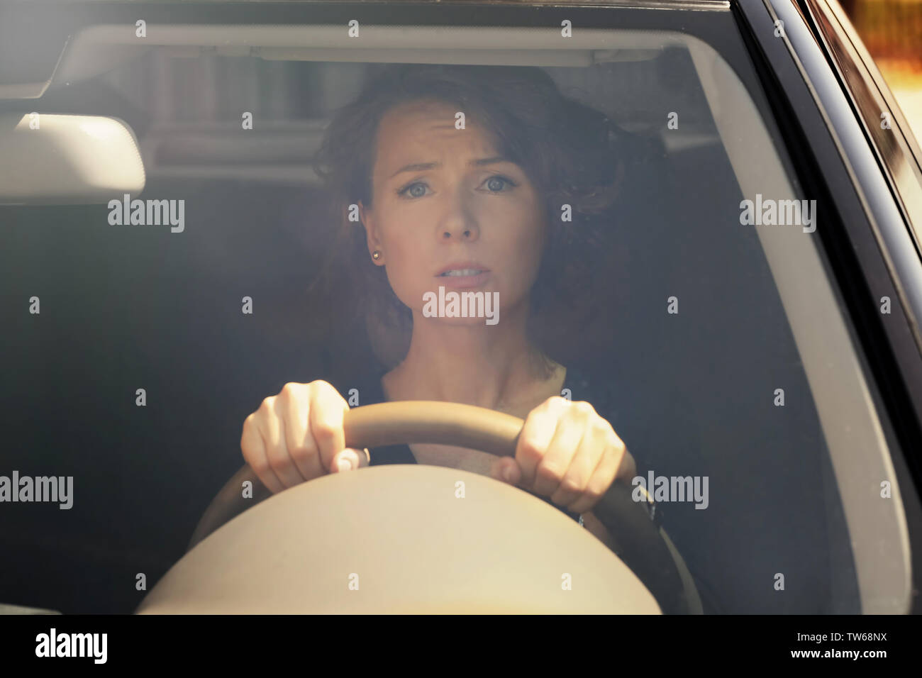 Emotional young woman driving a car, view from outside through ...