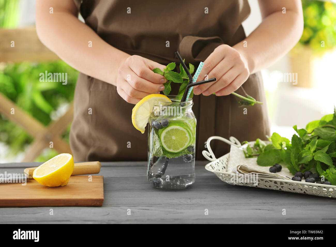 Woman preparing infused water with fruits in mason jar Stock Photo - Alamy