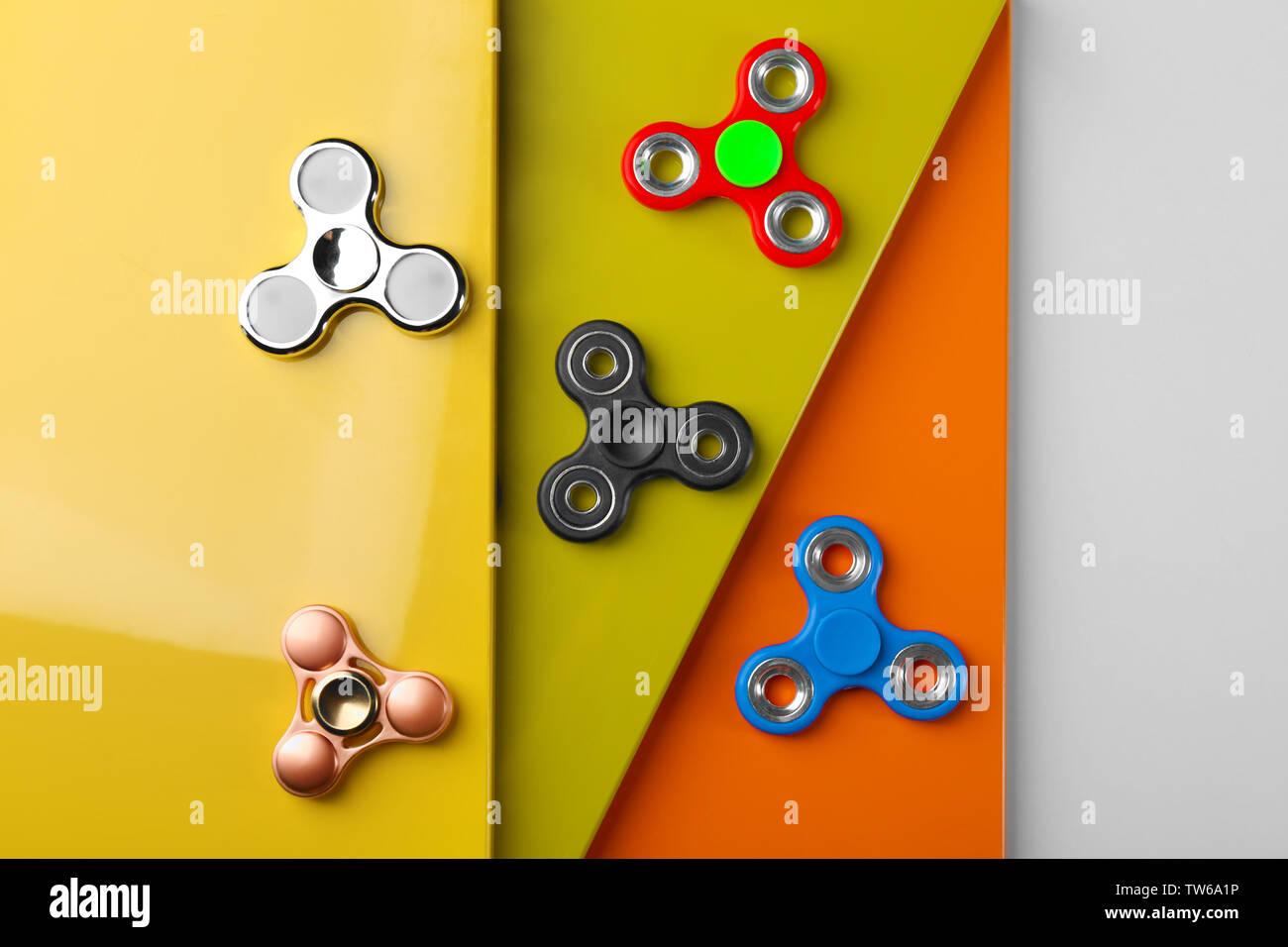 Different modern spinners on colorful background, top view Stock Photo ...