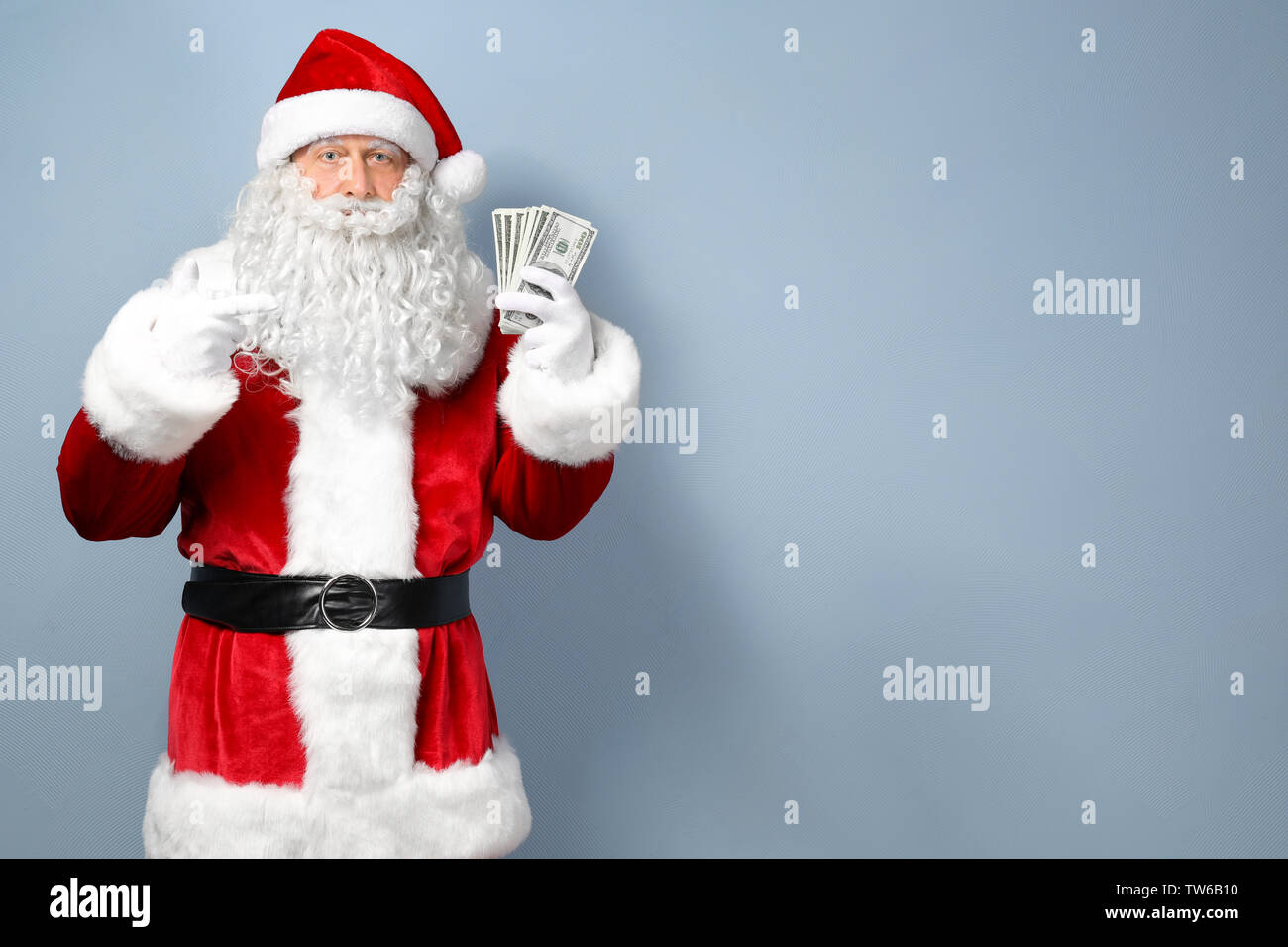 Santa Claus holding money on light background Stock Photo - Alamy