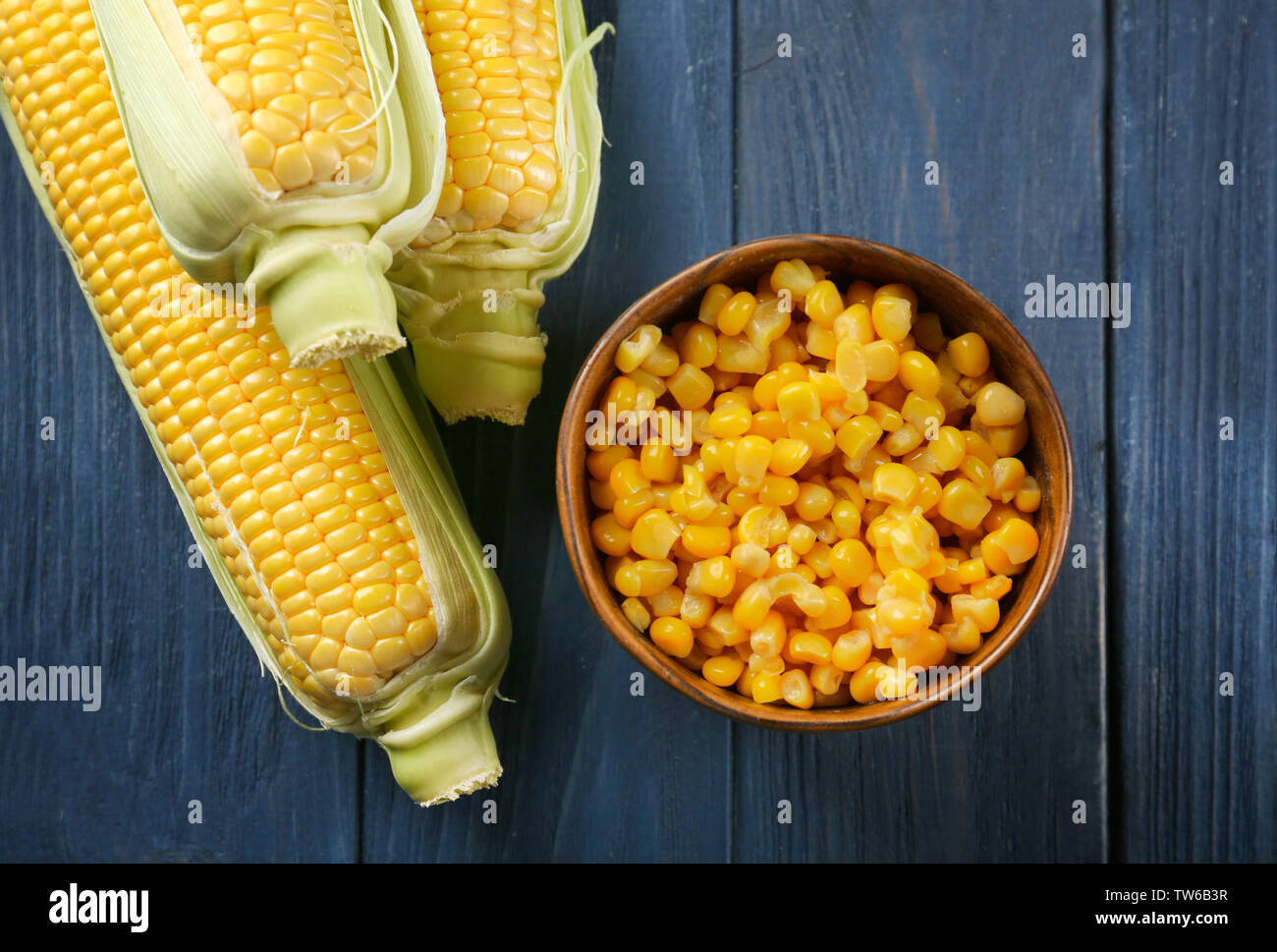 Corn cobs and bowl with kernels on wooden background Stock Photo - Alamy