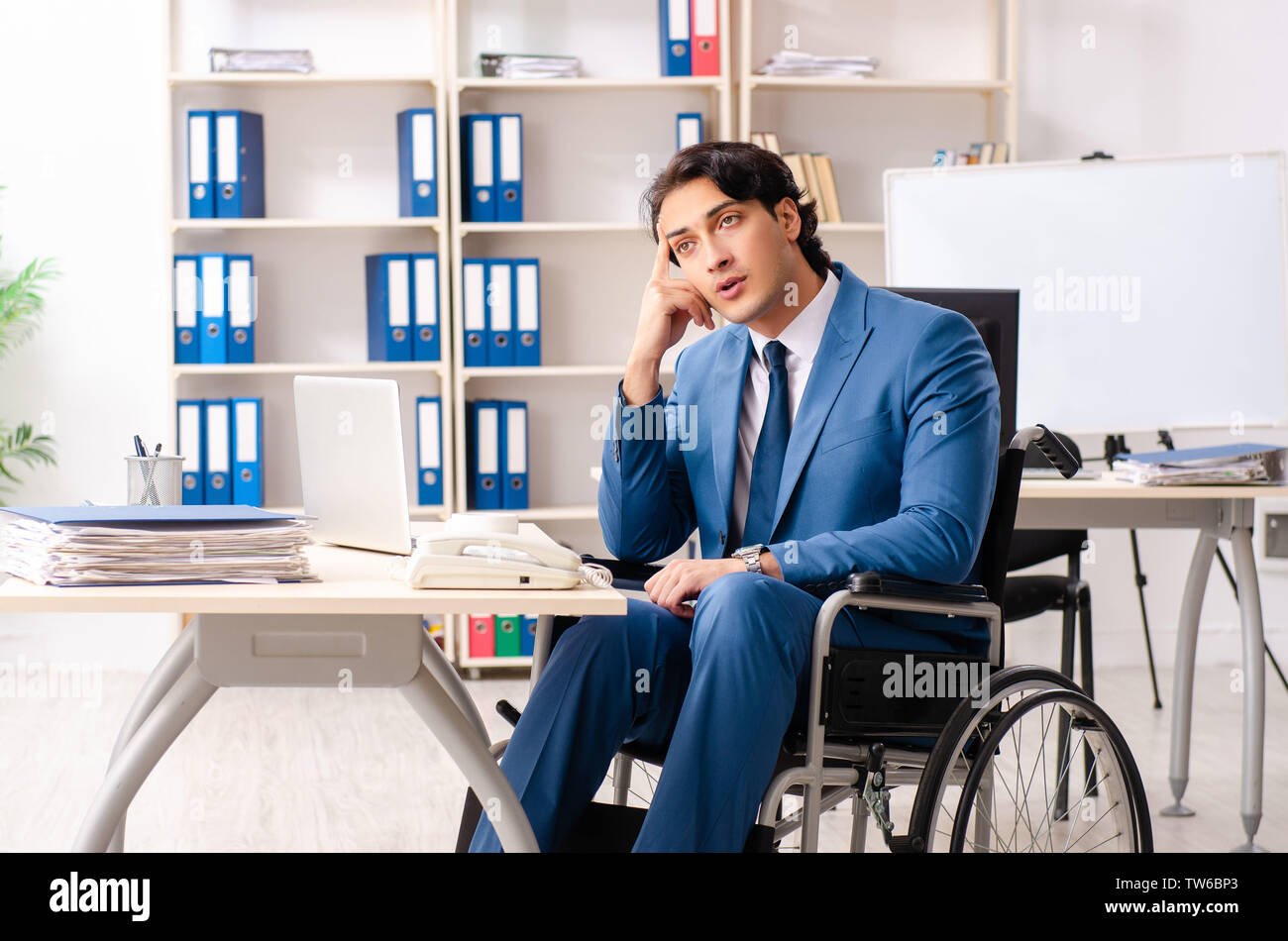 Male employee in wheelchair working at the office Stock Photo - Alamy