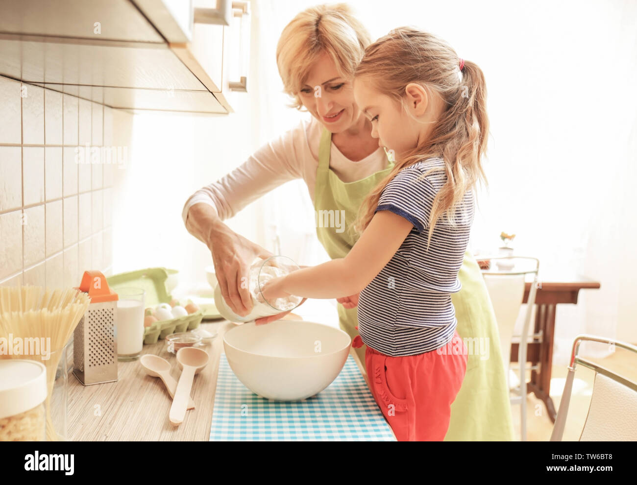 Cute little girl and her grandmother cooking in kitchen Stock Photo - Alamy