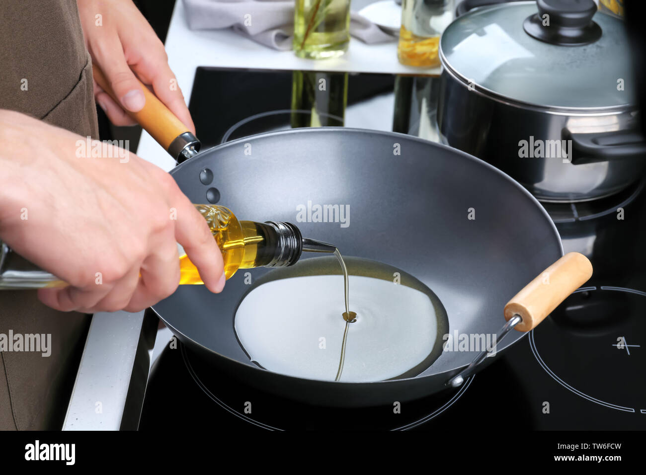 Man pouring cooking oil from bottle into frying pan on stove Stock ...
