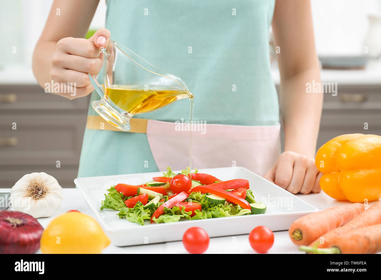 Woman pouring cooking oil onto vegetable salad in kitchen Stock Photo ...