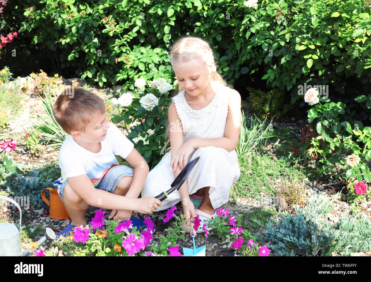 Cute little children planting flowers in garden Stock Photo - Alamy