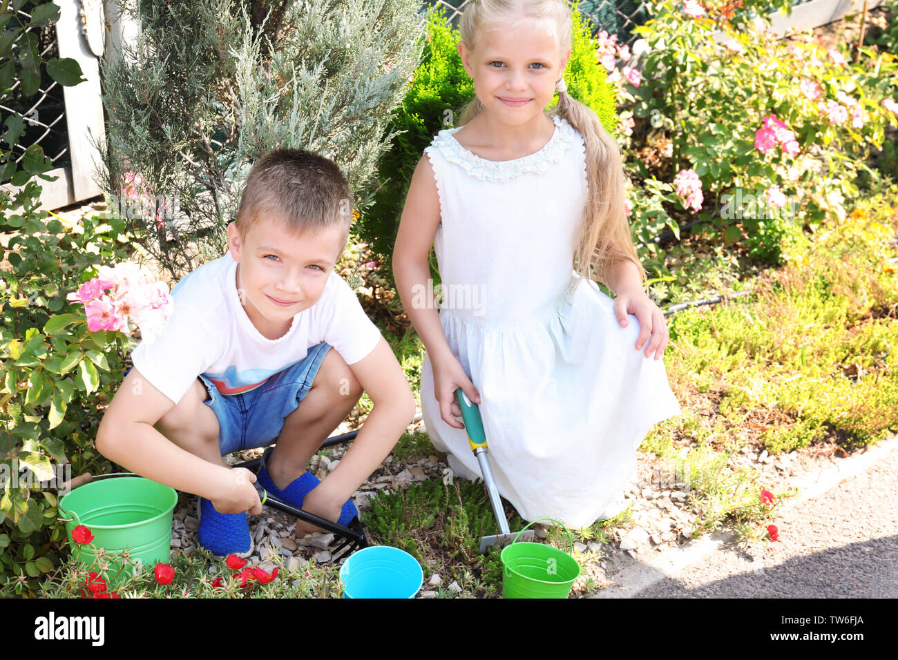 Cute little children planting flowers in garden Stock Photo - Alamy