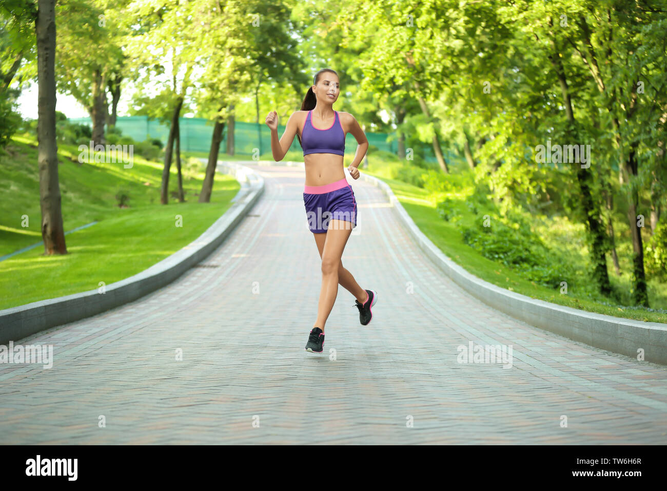Sporty young woman running in park Stock Photo - Alamy