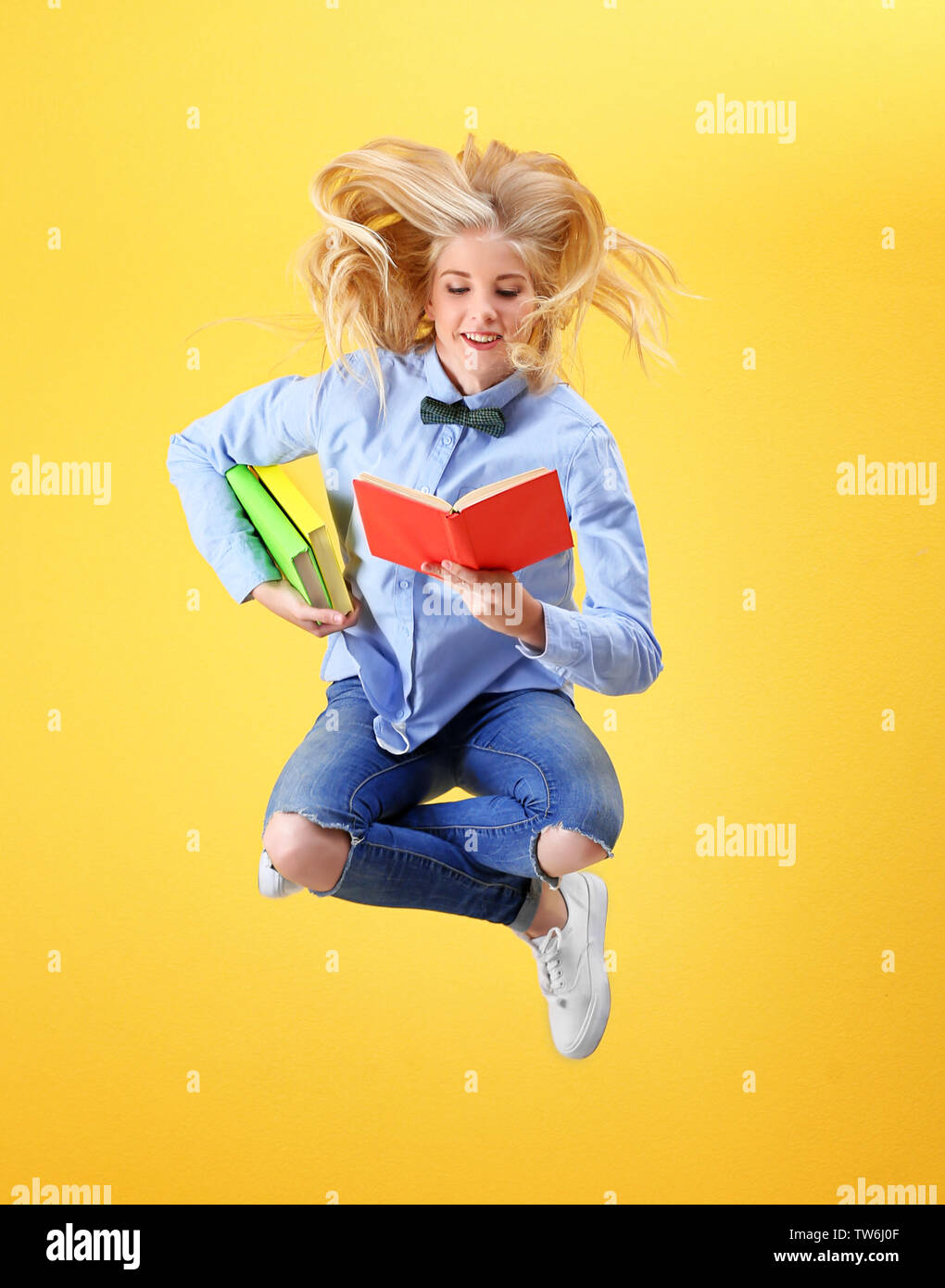 Jumping teenager girl with books on color background Stock Photo - Alamy