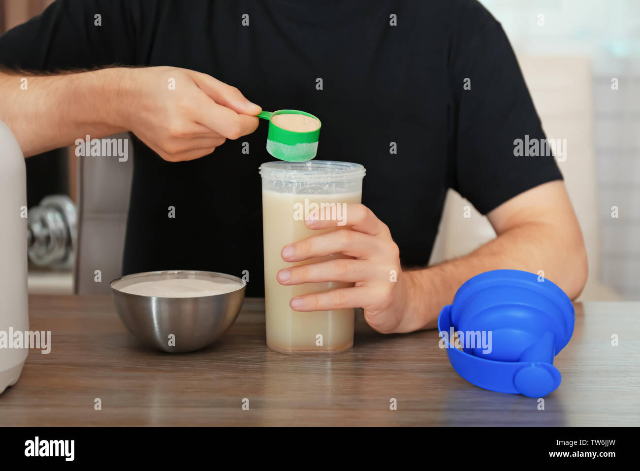 Man adding protein powder into plastic bottle on table Stock Photo - Alamy