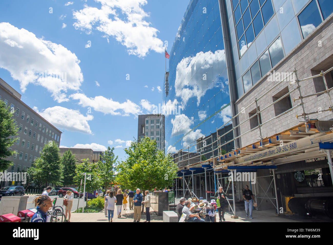 Mirrored office building reflects big white clouds and blue skies over ...