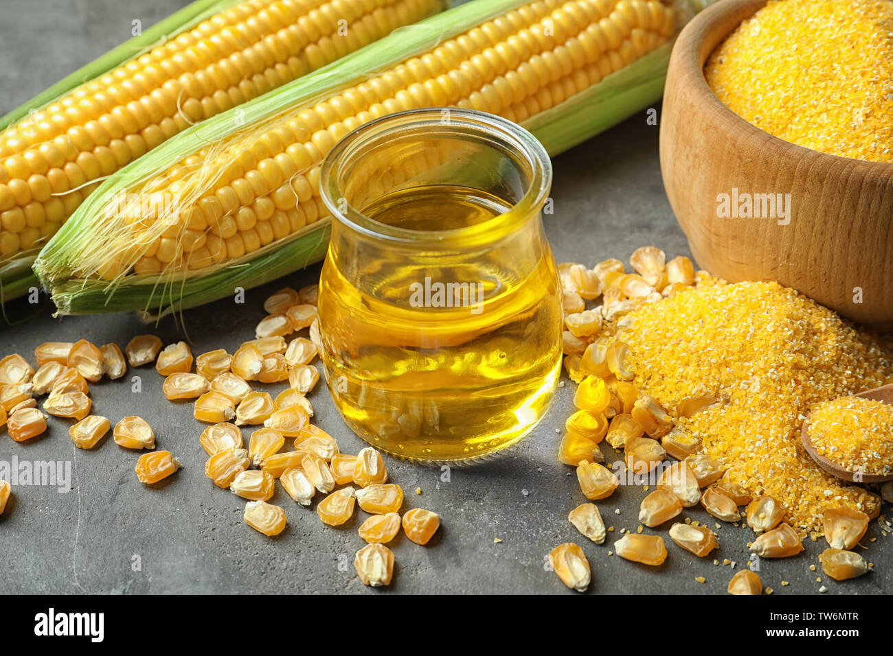 Composition with corn oil, flour and dried kernels on grey background ...
