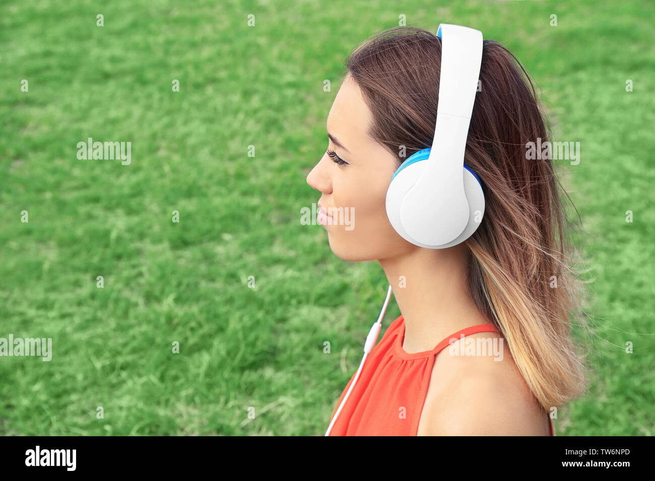 Beautiful young woman relaxing while listening to music outdoors Stock ...