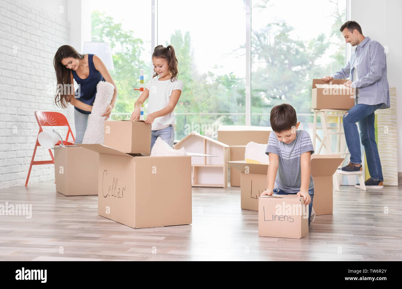 Happy family unpacking moving boxes in room at new home Stock Photo - Alamy