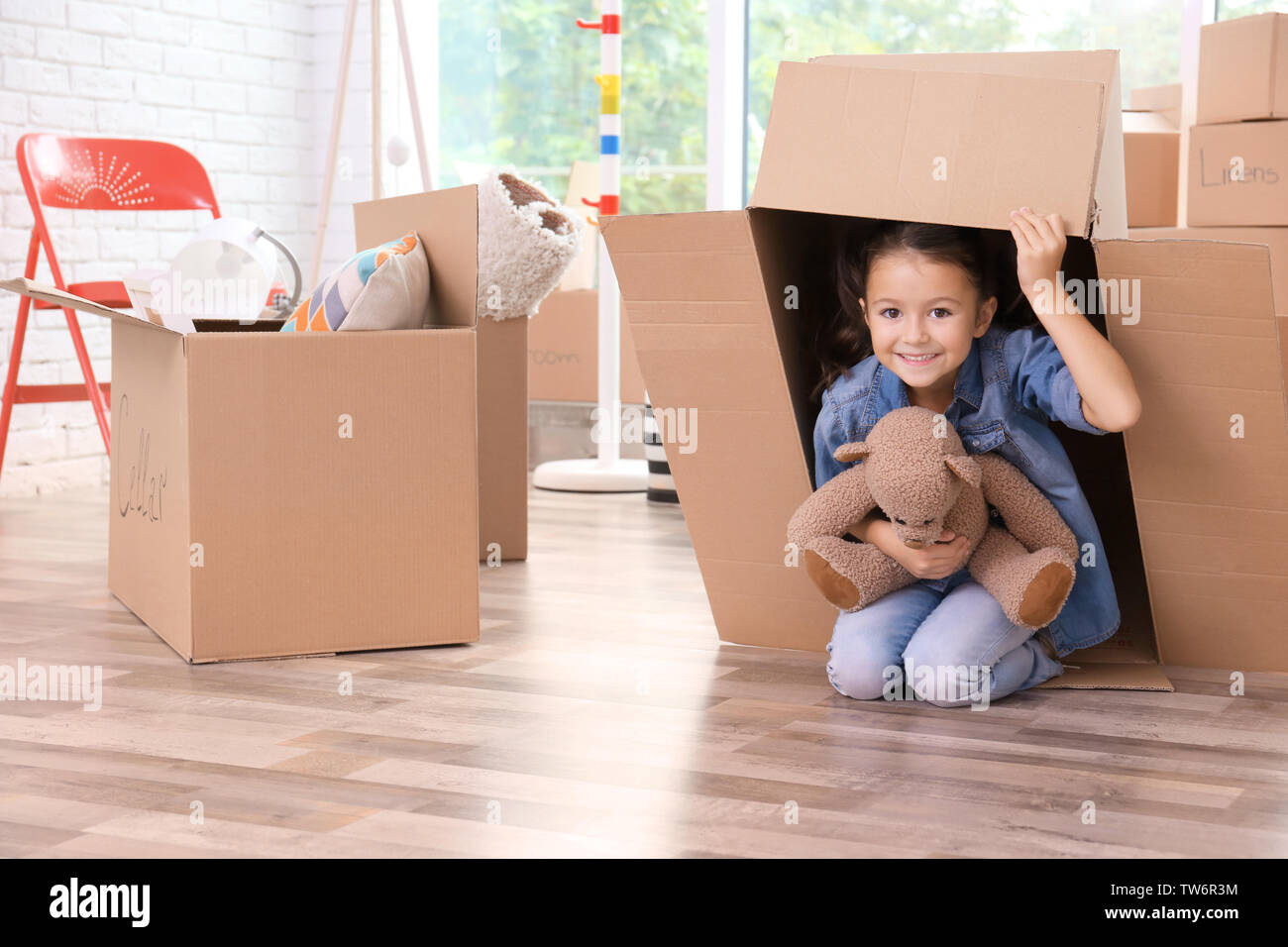 Cute little girl in moving box at new home Stock Photo - Alamy