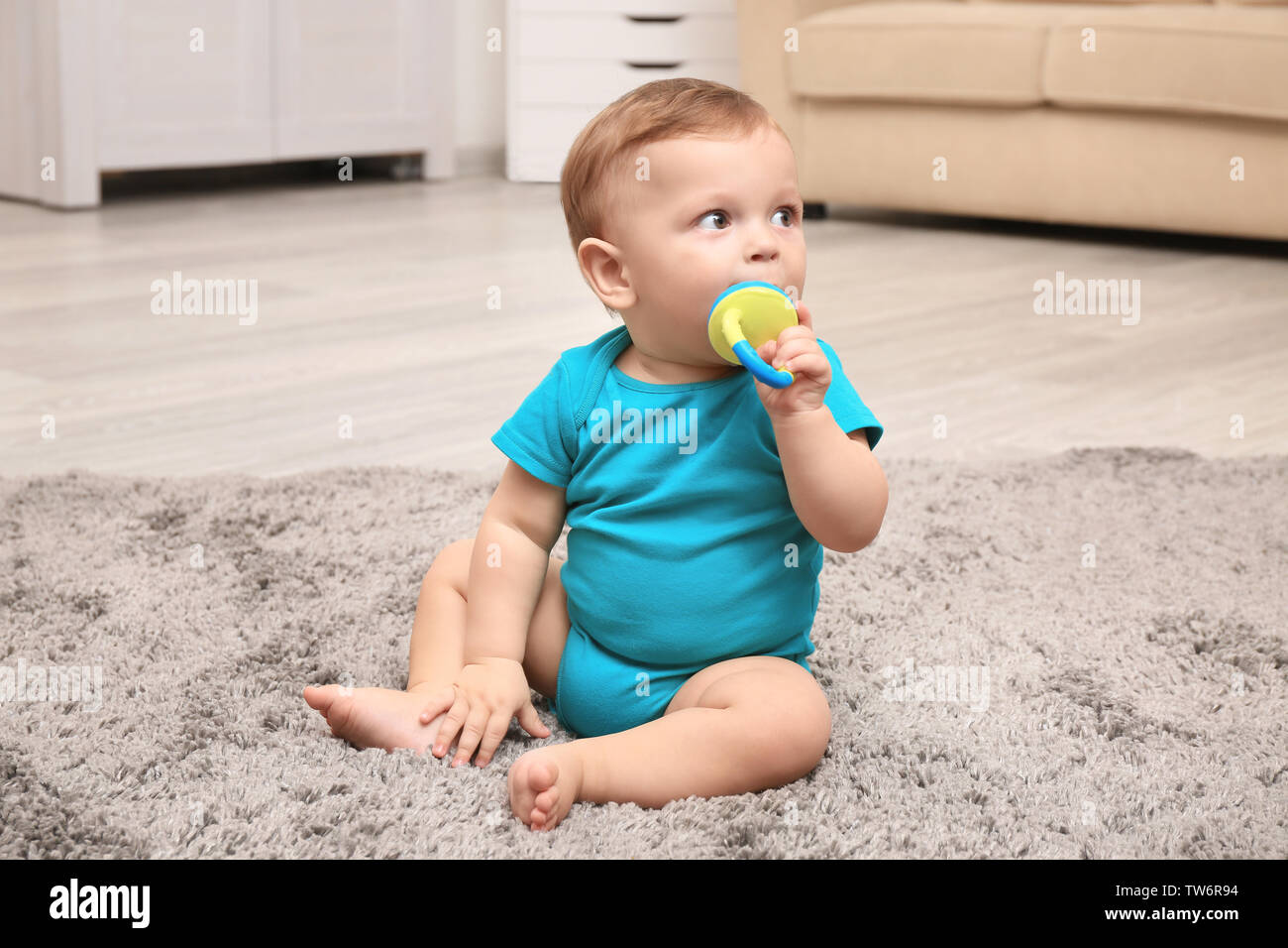 Cute little baby with nibbler on carpet Stock Photo - Alamy