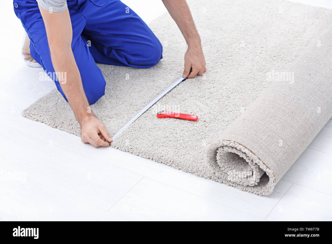 Male worker fitting carpet on floor indoors Stock Photo - Alamy