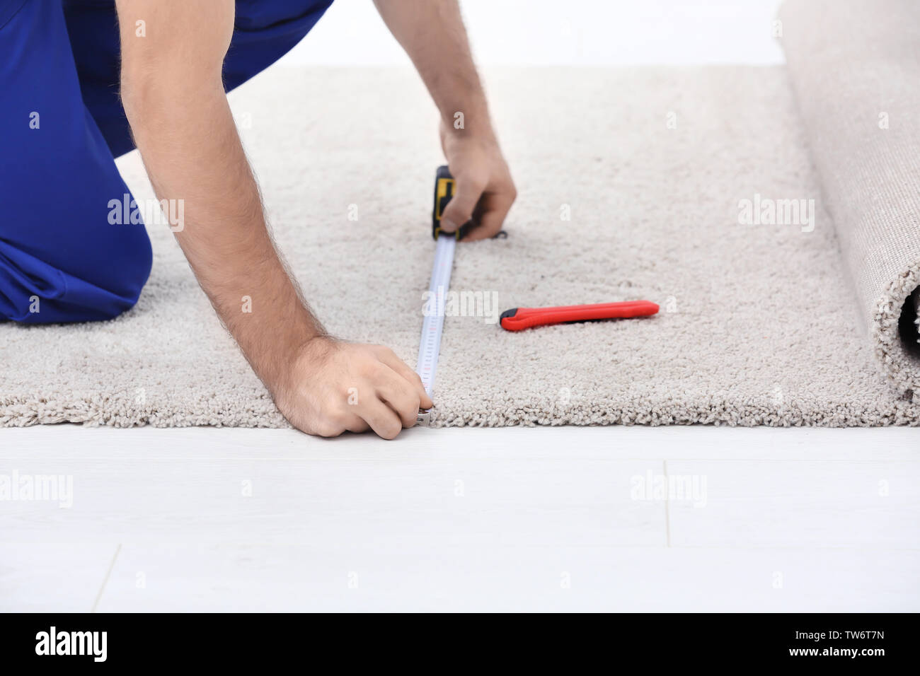 Male worker fitting carpet on floor indoors Stock Photo - Alamy