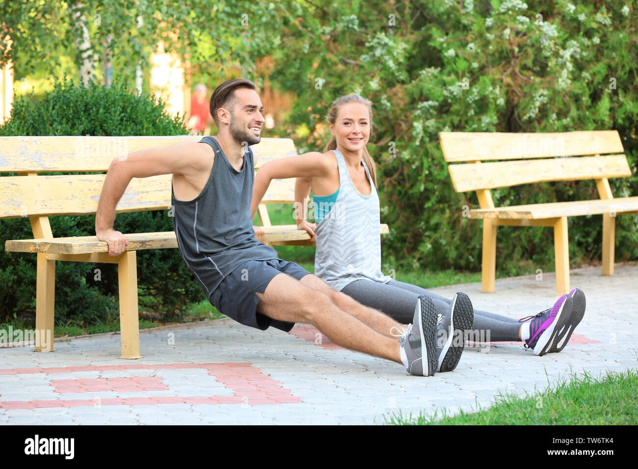 Young man and woman doing exercises in park Stock Photo - Alamy