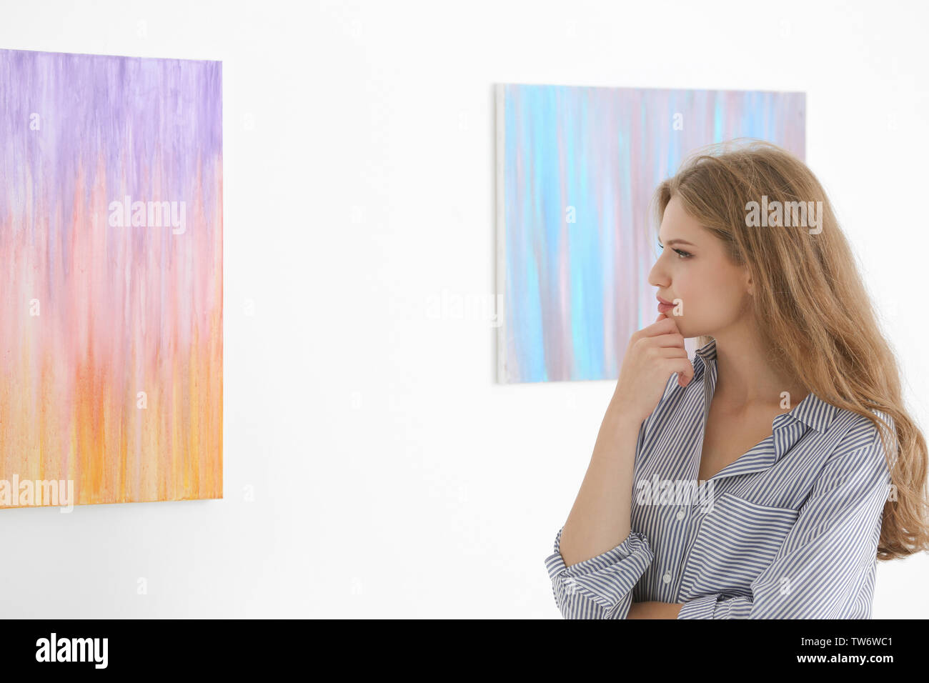 Young woman looking at painting in art gallery Stock Photo - Alamy