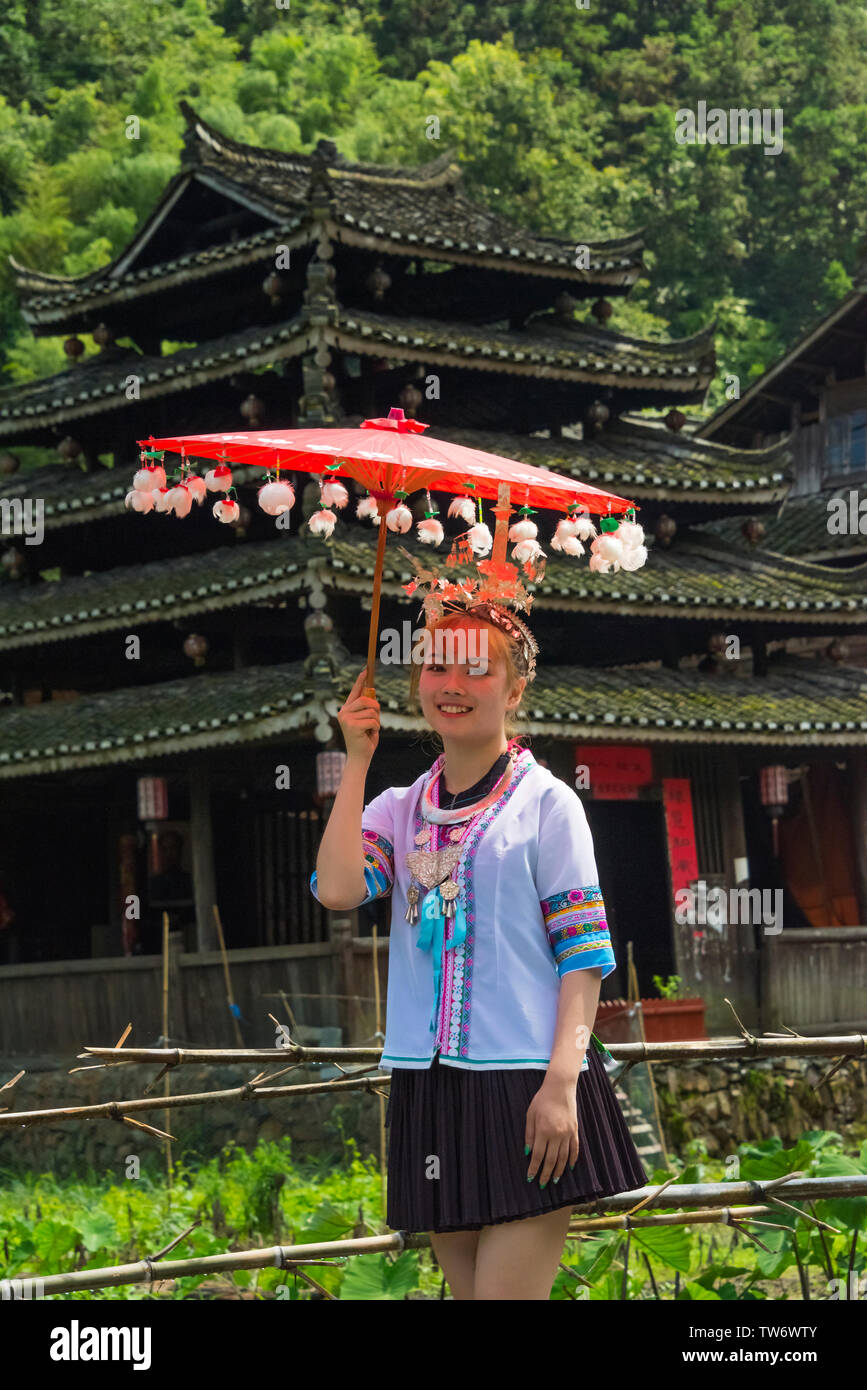 Dong girl in traditional clothing with a red umbrella, Hunan Province ...