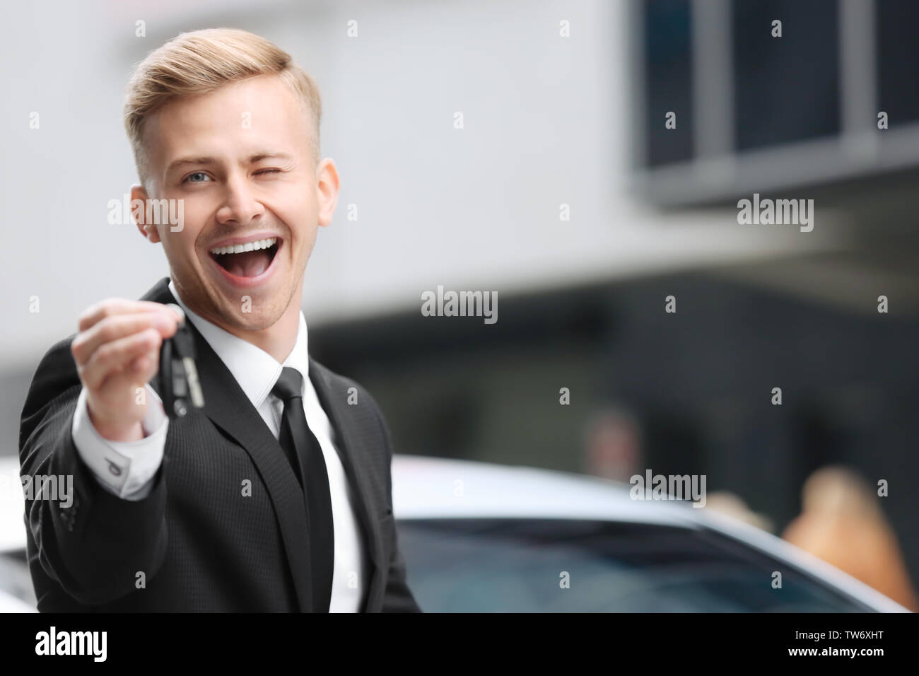 Young car salesman in formal suit handing key outdoors Stock Photo - Alamy