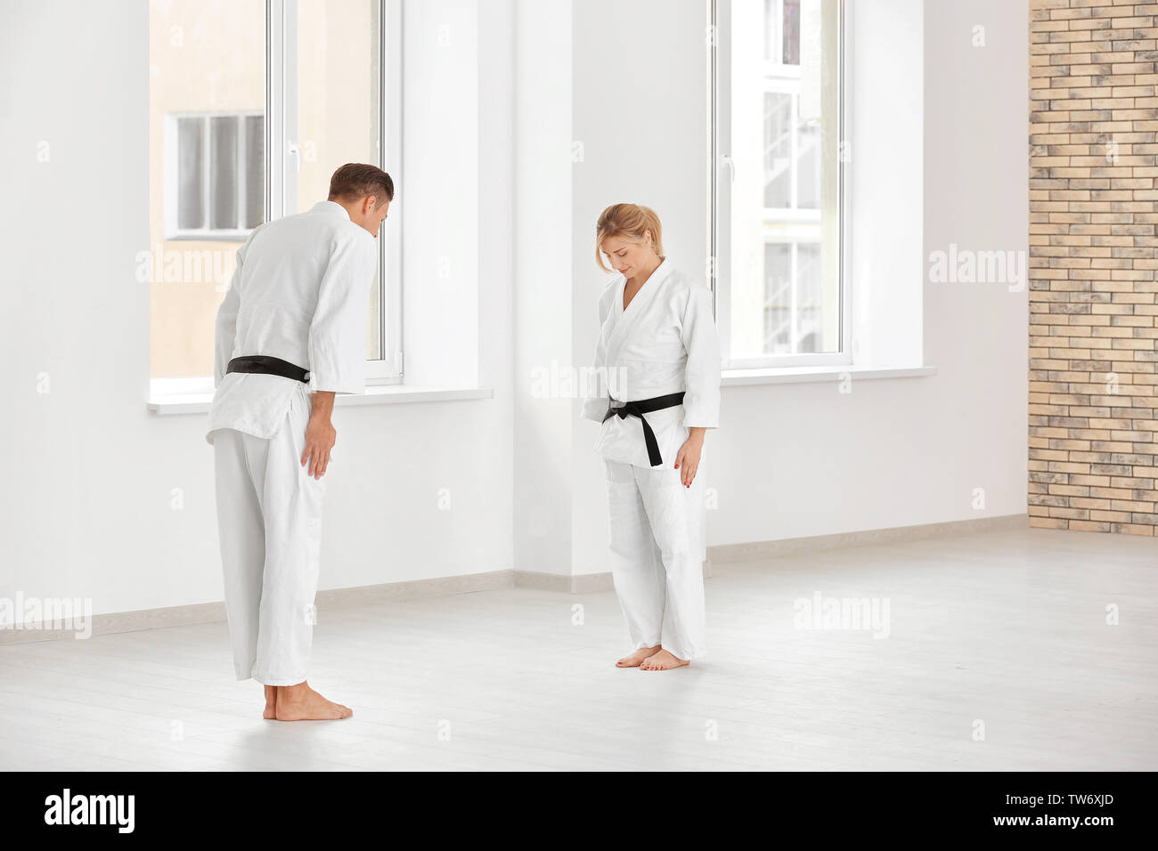 Young man and woman performing ritual bow prior to practicing karate in ...