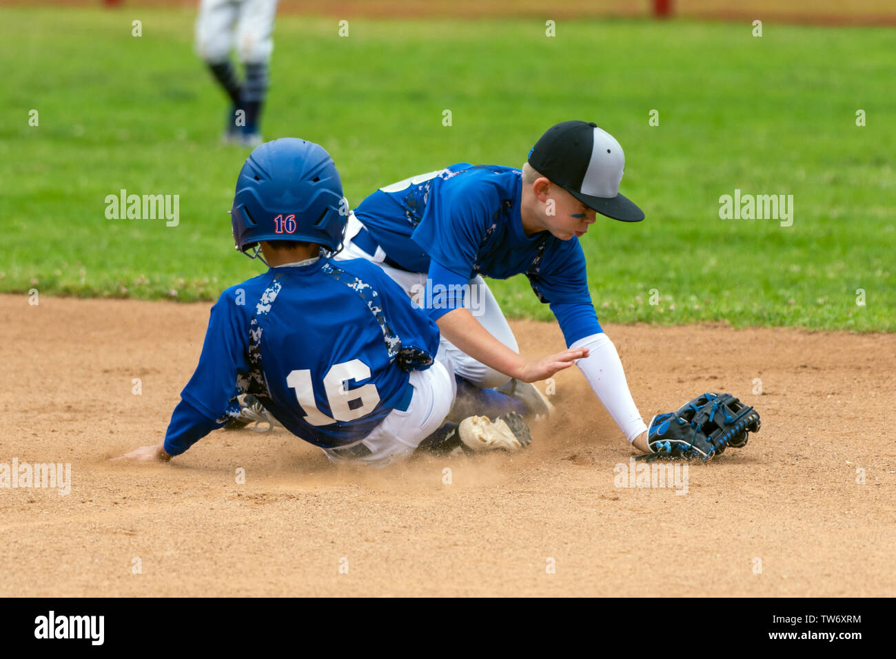 Youth baseball player in blue uniform playing short stop withstanding ...