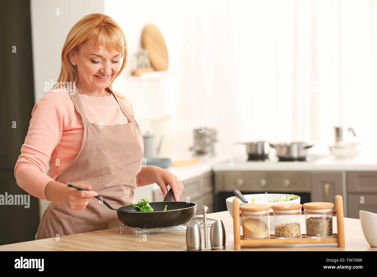Beautiful mature woman cooking in kitchen Stock Photo - Alamy