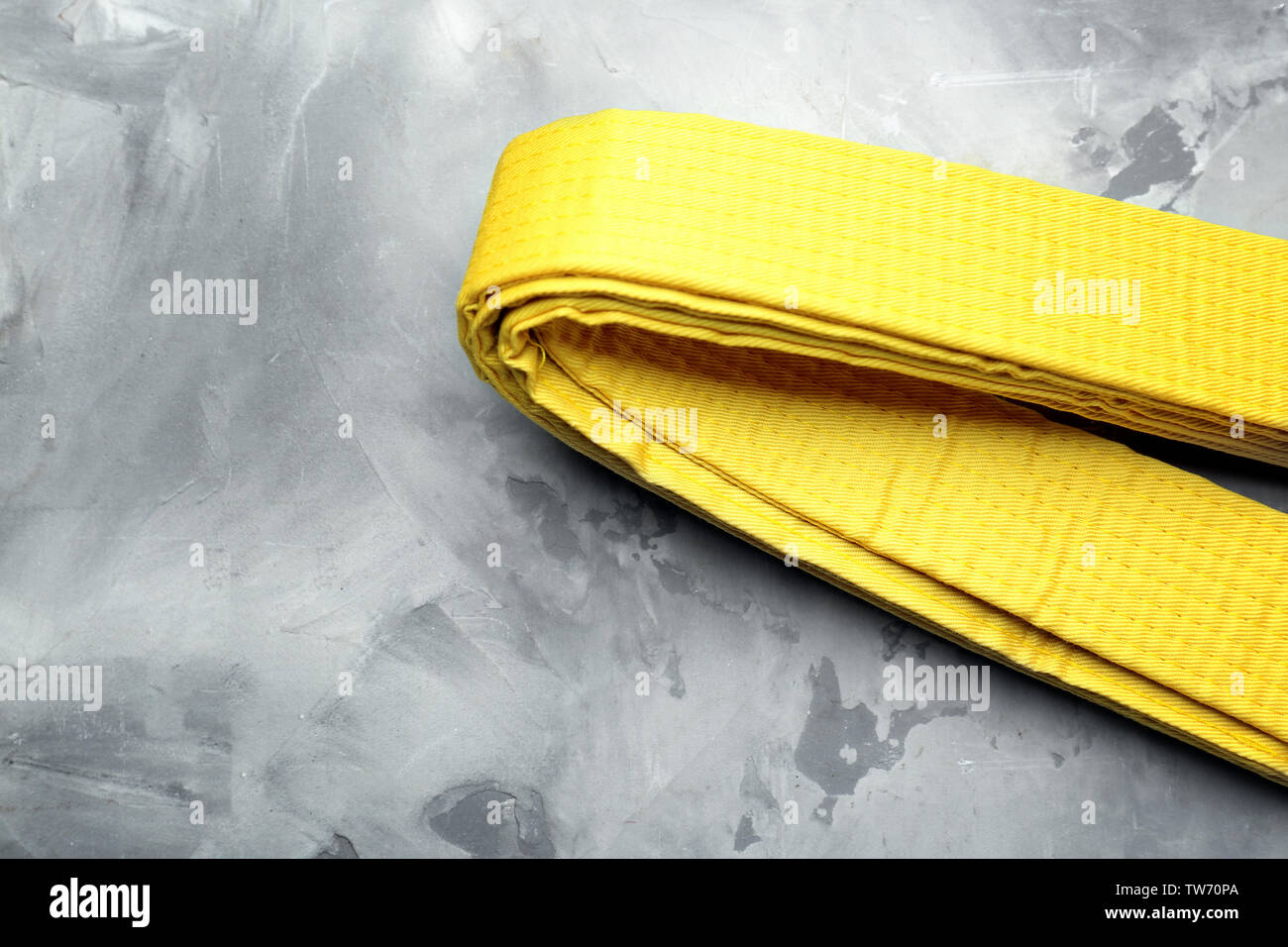 Yellow karate belt on grey background Stock Photo - Alamy